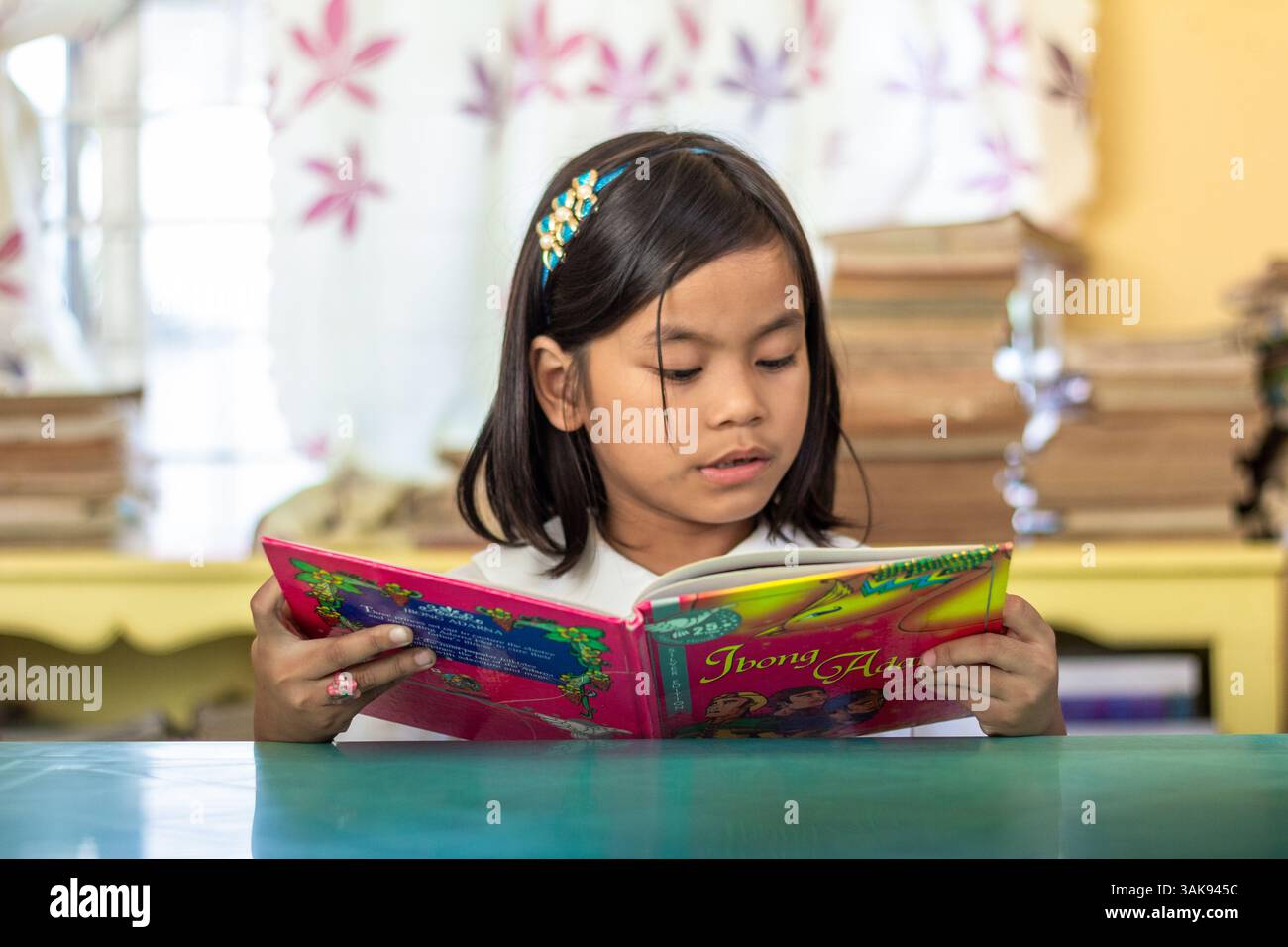 A young Filipino student reading a children's book inside a public ...