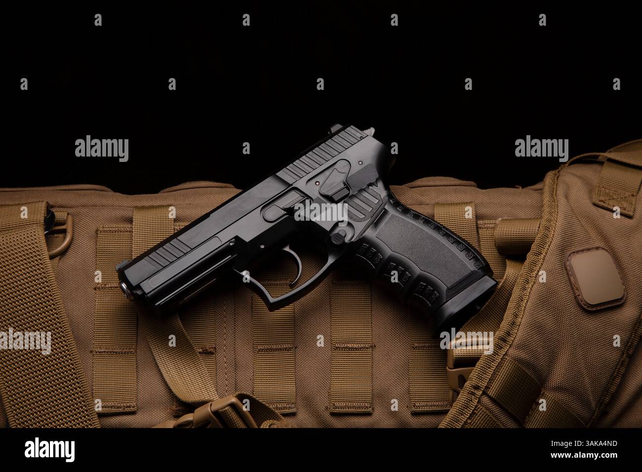Black tactical pistol resting on brown military backpack, top-down view ...
