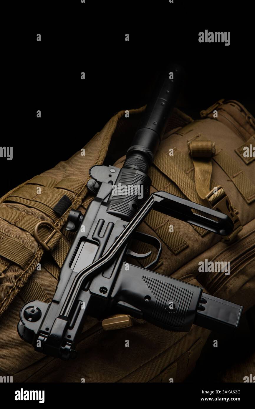 Black submachine gun with suppressor lying on brown tactical backpack ...