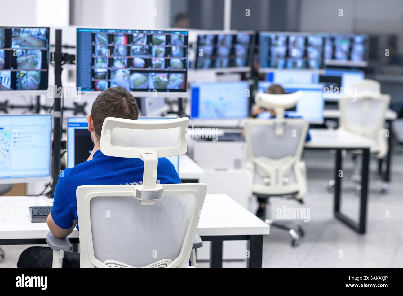 Security officer monitoring multiple surveillance screens in a high-tech control room for safety ...