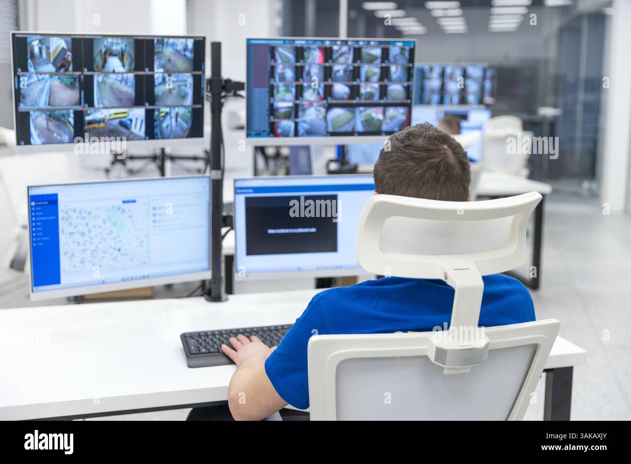Security officer monitoring multiple surveillance screens in a high-tech control room for safety ...
