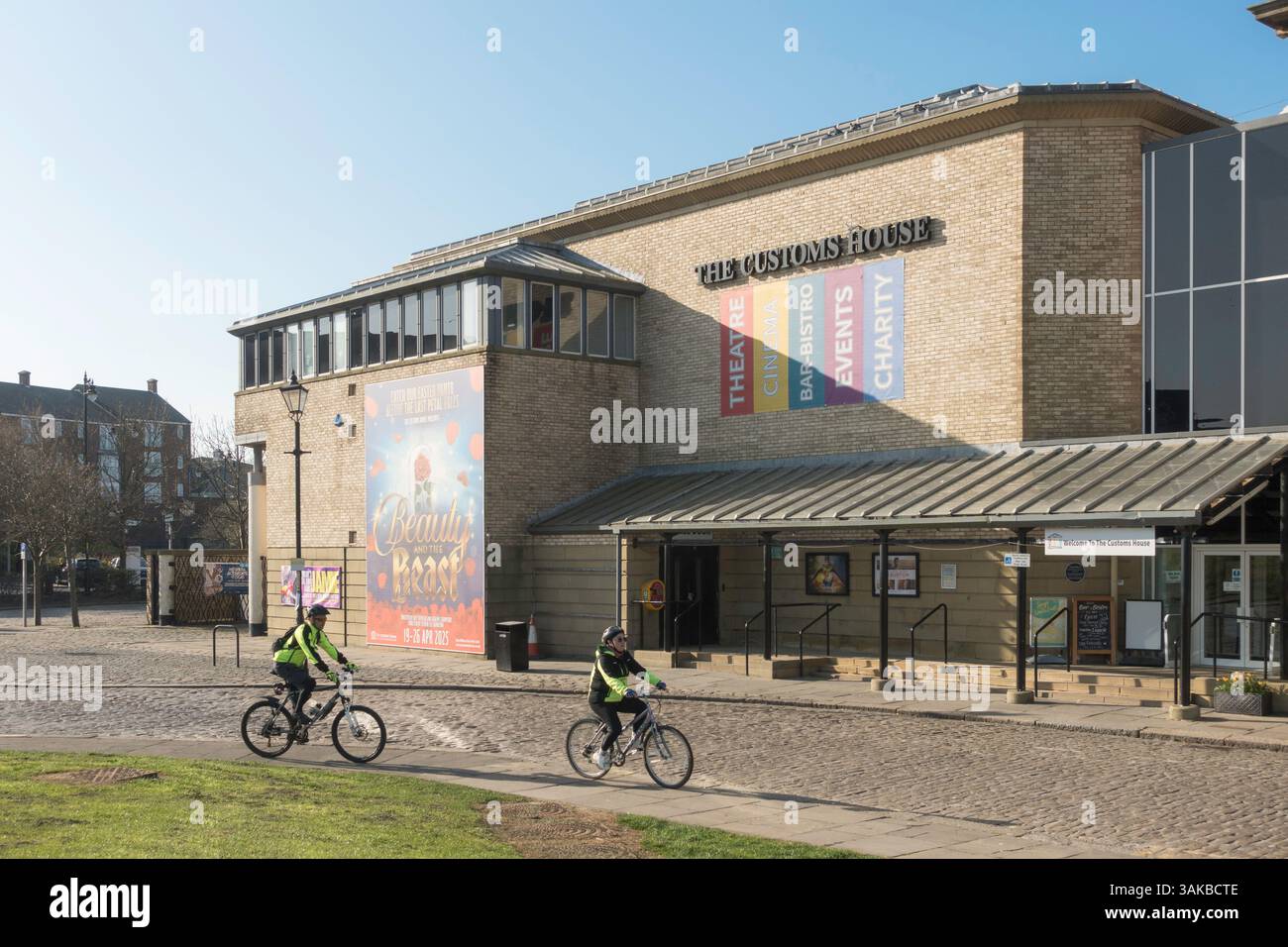 Two cyclists passing The Customs House Theatre in South Shields ...