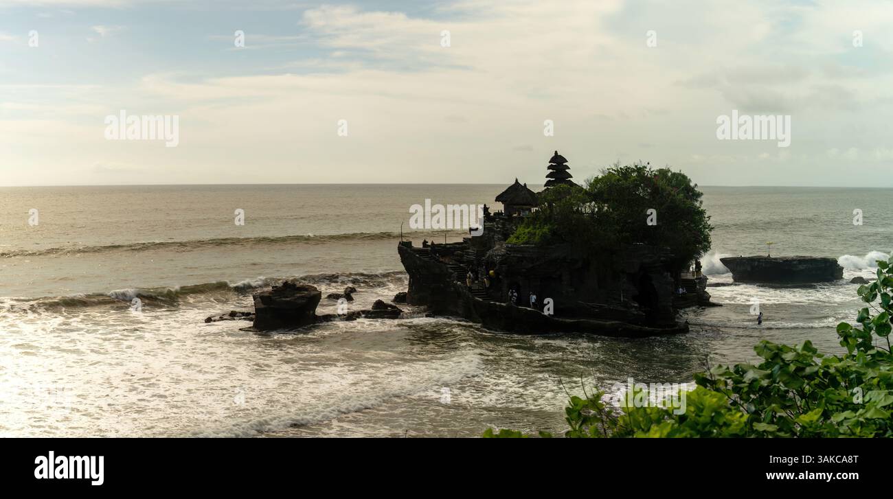 Tanah Lot Temple in Bali rises above the sea on a rugged rock formation ...