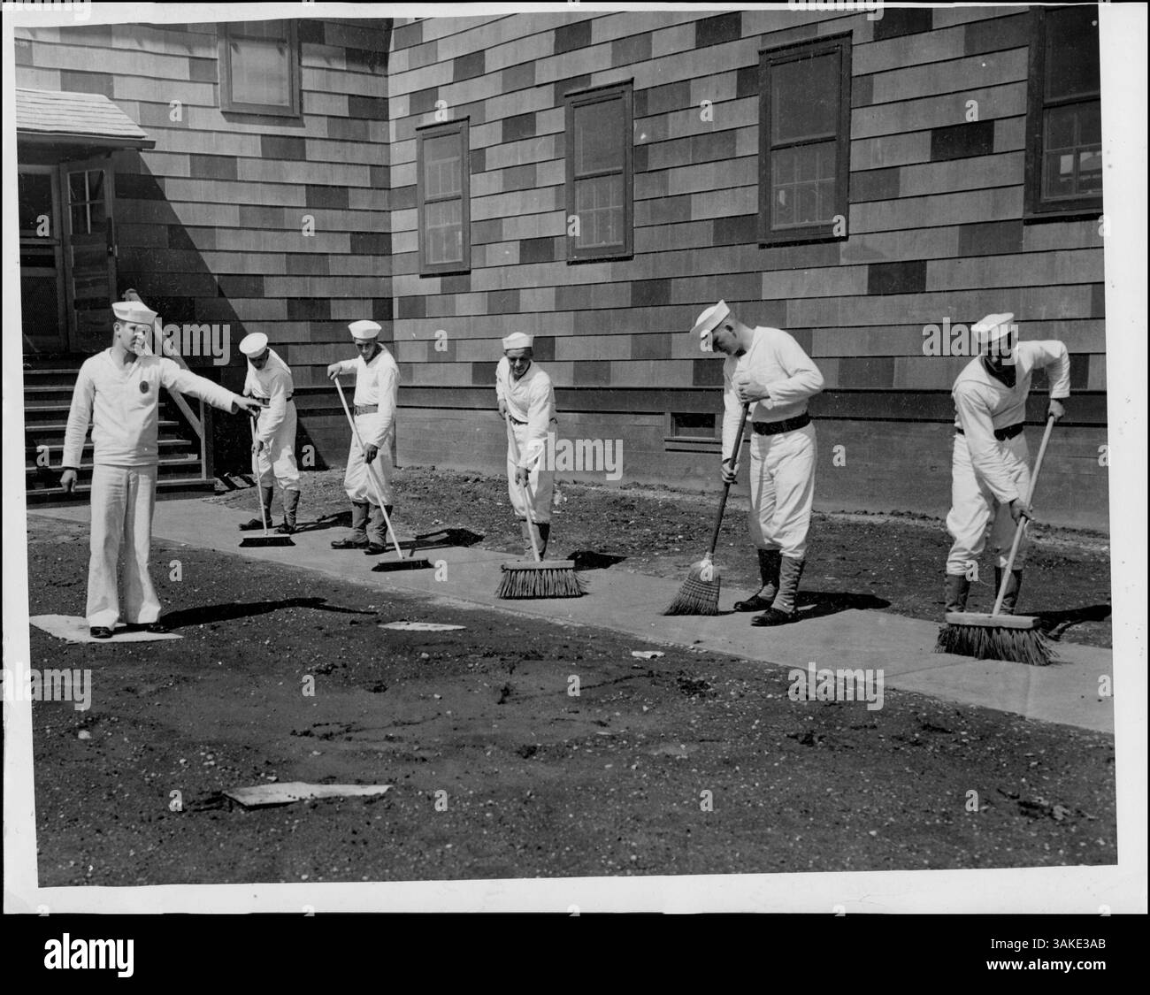 The image shows a group of soldiers cleaning the grounds around the ...