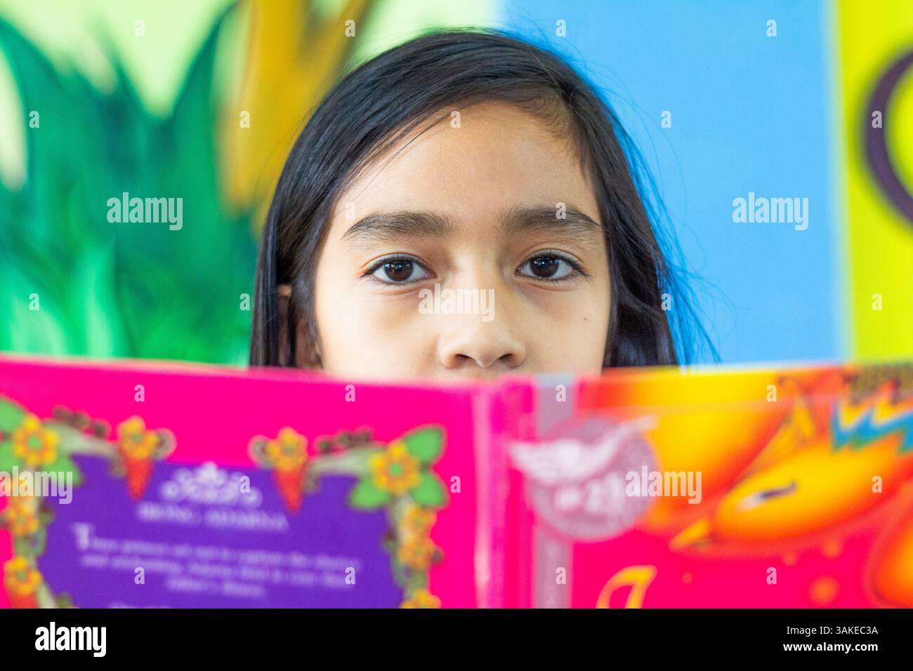 A young Filipino student reading a children's book inside a public ...
