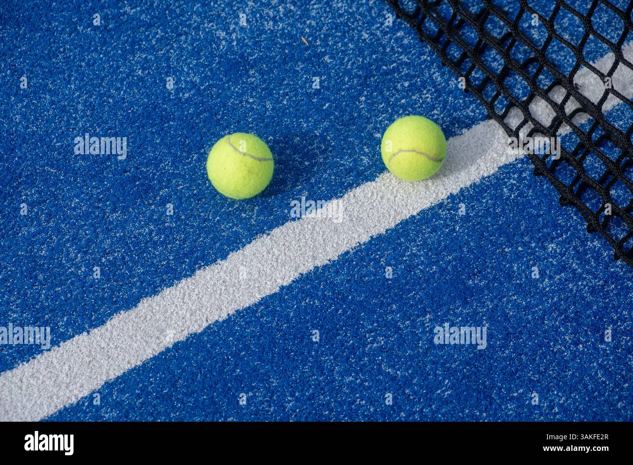 two padel balls near the net in a blue paddle tennis court, background ...