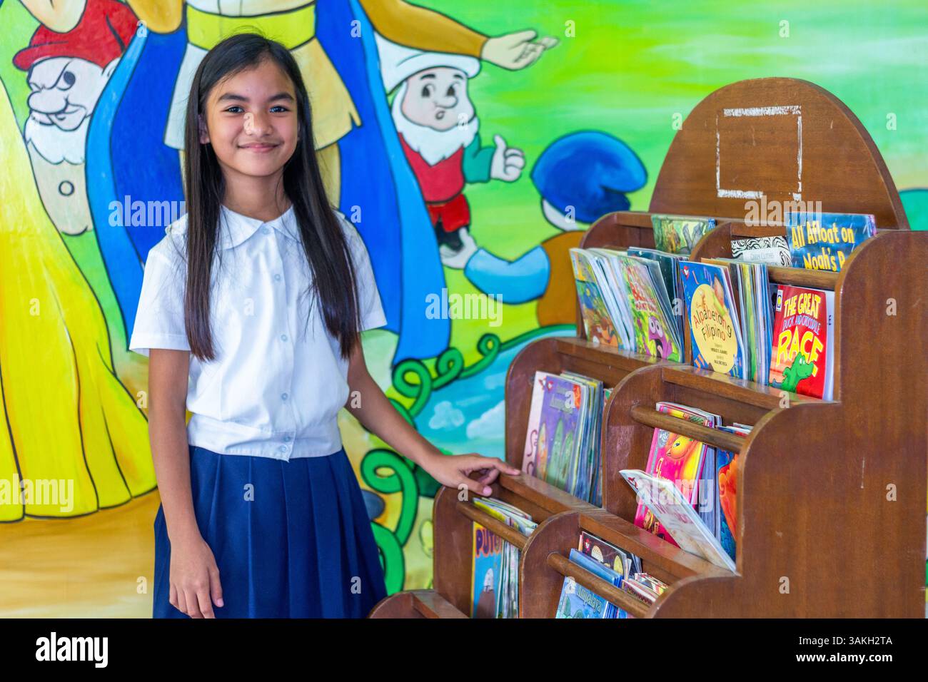 A young Filipino student reading a children's book inside a public ...