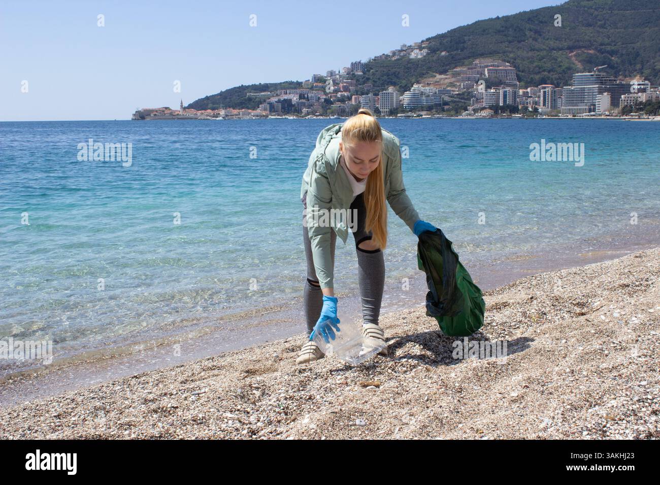 Woman volunteer helps clean the beach of garbage. Earth day and ...