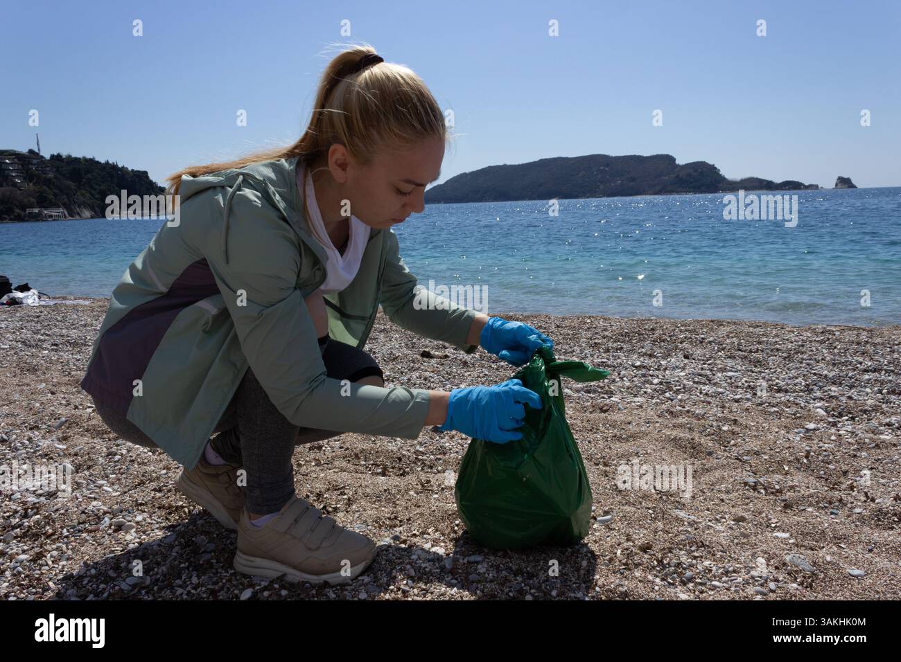 Woman volunteer helps clean the beach of garbage. Earth day and ...
