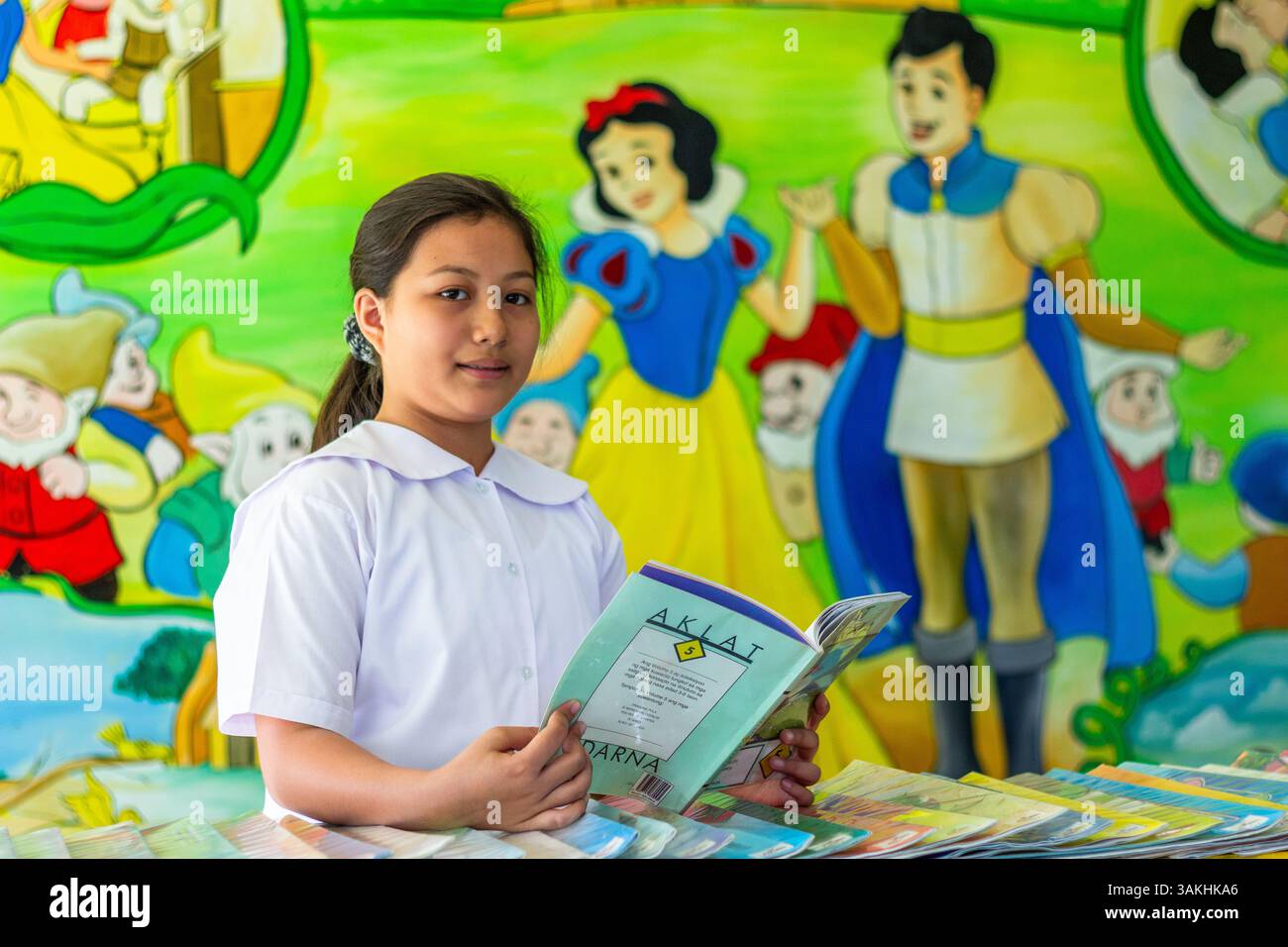 A young Filipino student reading a children's book inside a public ...