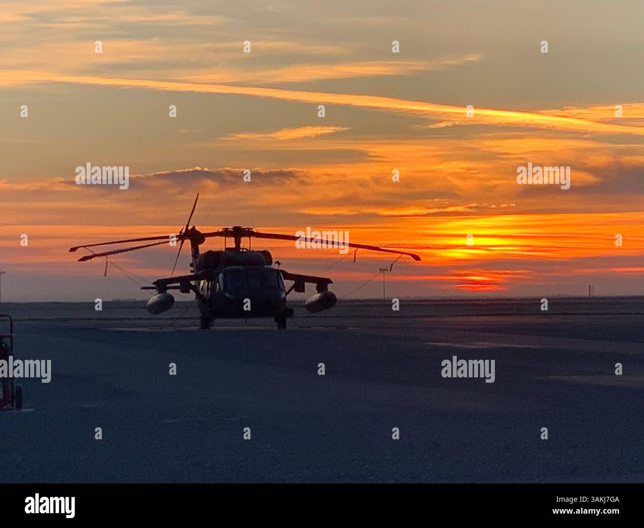 A UH-60 Black Hawk helicopter parks on the flight line at sunset at ...