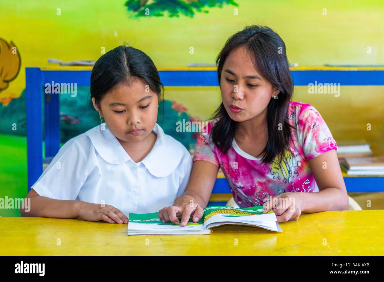 A Filipino mother reads with her daughter at a public elementary school ...
