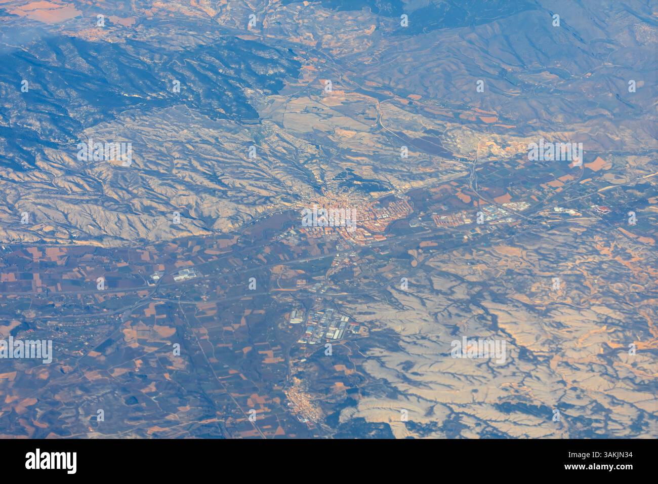 Aerial view reveals a sprawling town nestled among rugged, arid ...
