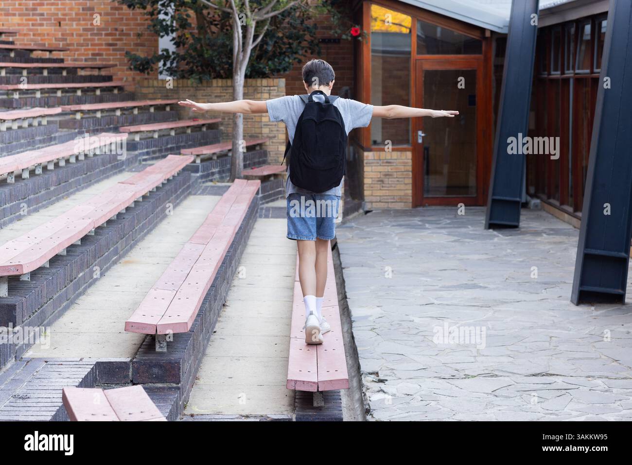 Balancing on bench, boy with backpack enjoying outdoor activity at ...