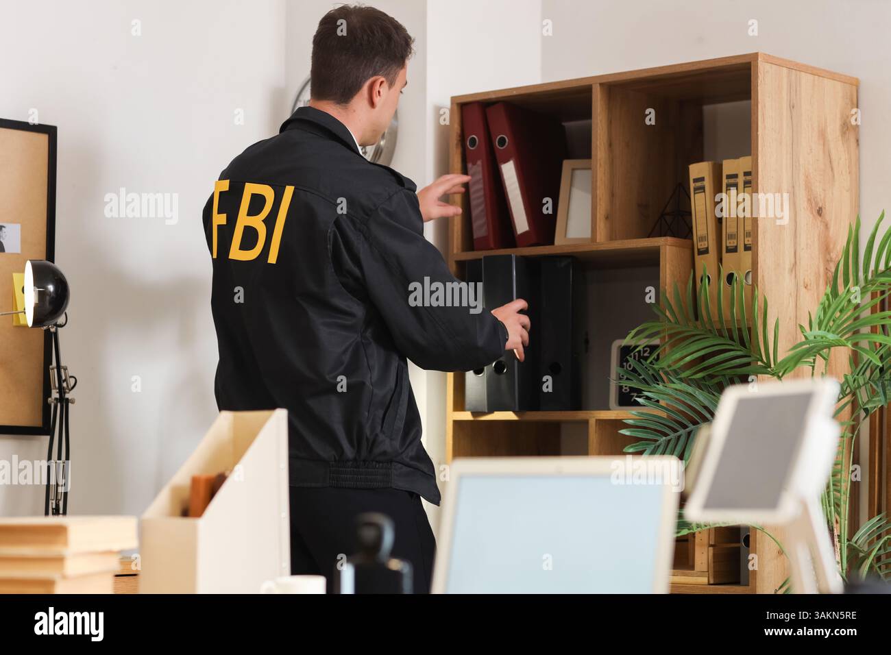 Male FBI agent taking folder from shelf in office, back view Stock ...