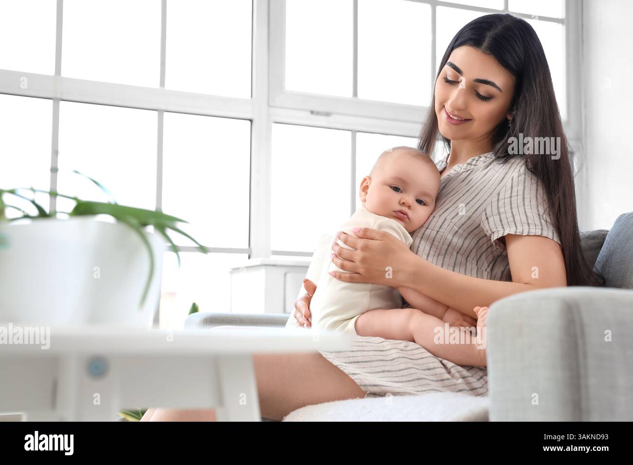 Happy mother hugging her little baby on sofa at home Stock Photo - Alamy