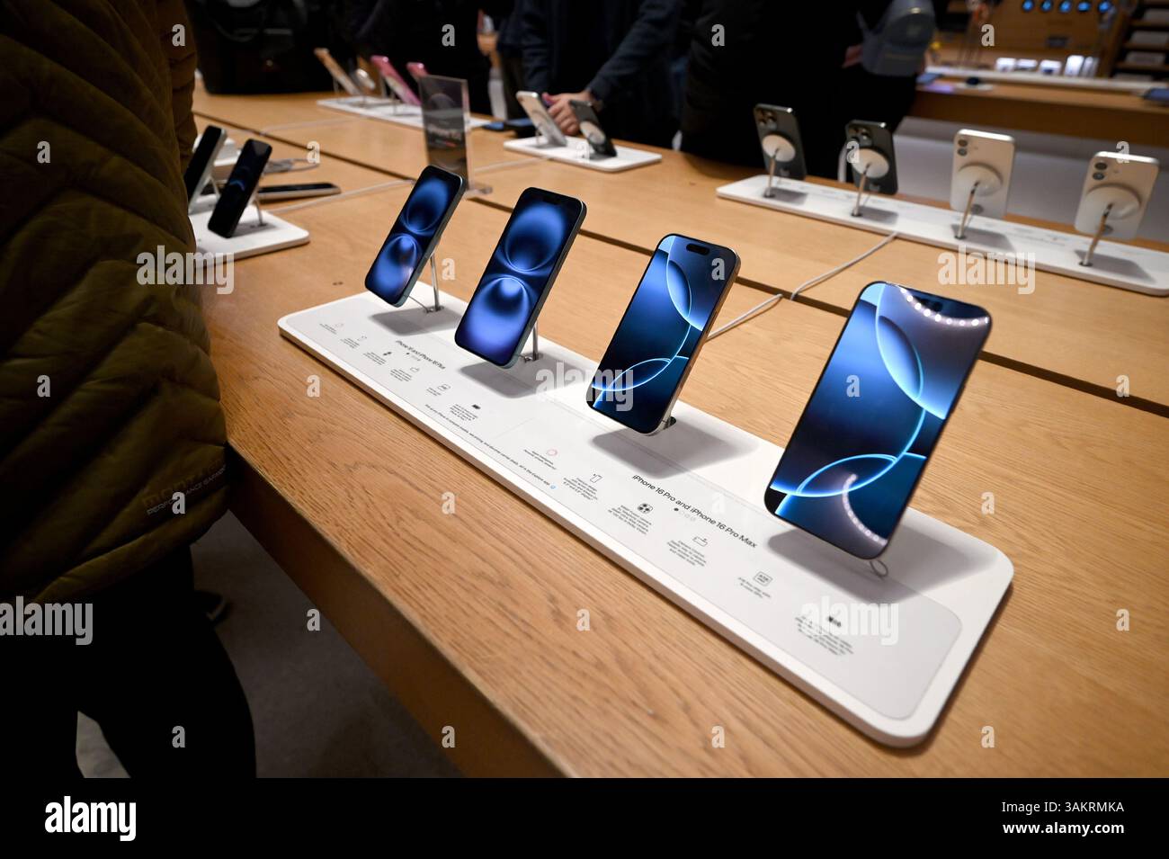 View of people looking at iPhones on display at an Apple retail store ...