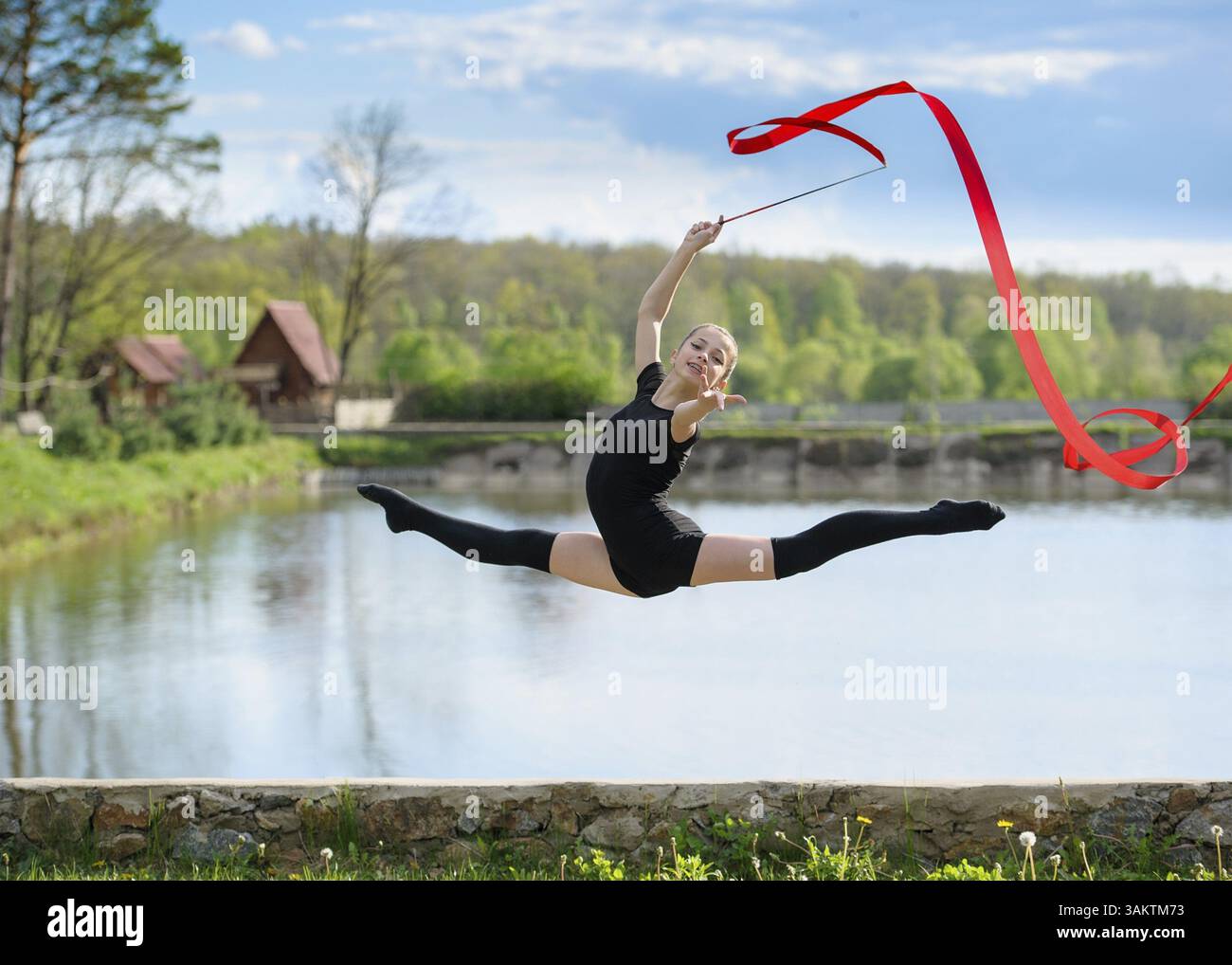 Young rhythmic gymnast doing split jump during ribbon exercises Stock ...