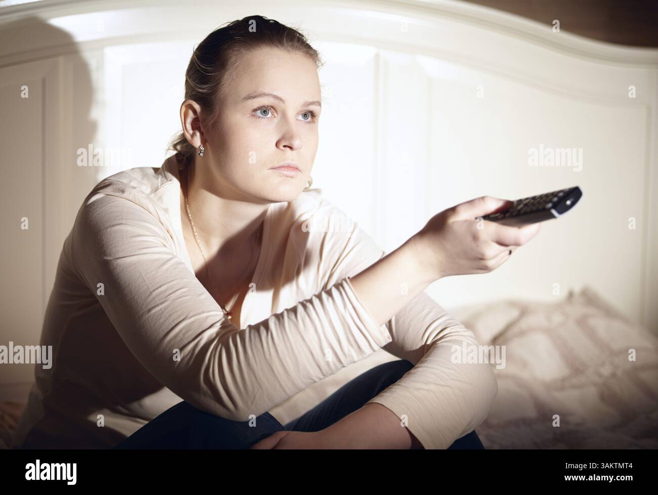 Young woman is watching tv with remote control Stock Photo - Alamy