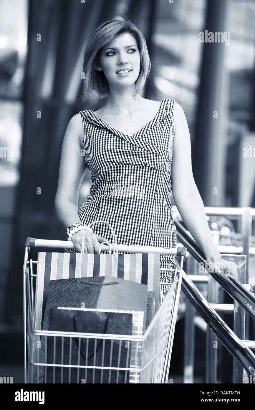 Beautiful blonde with shopping cart near supermarket Stock Photo - Alamy
