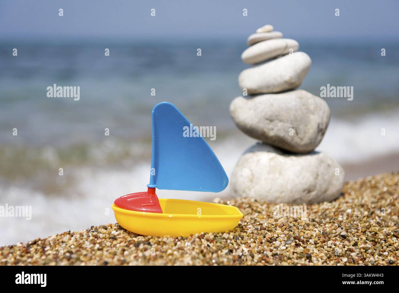 Toys and stacked pebbles at the beach Stock Photo - Alamy