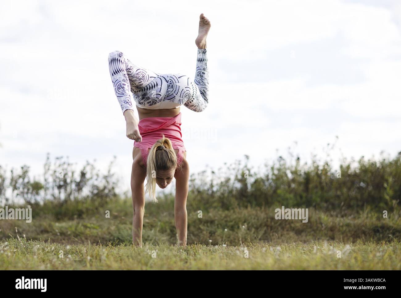 Agile young woman doing a handstand outdoors in the countryside ...