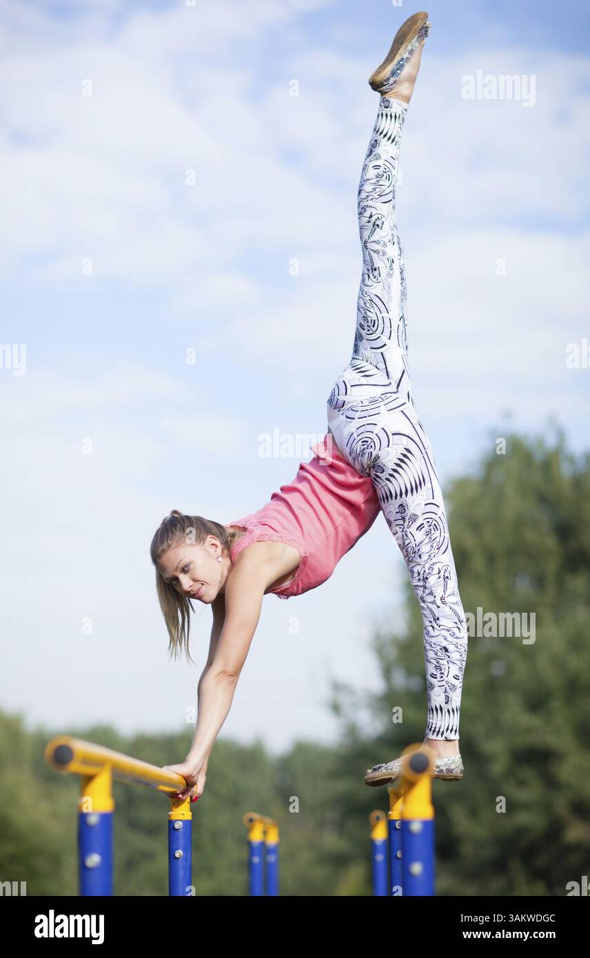 Agile attractive young female gymnast balancing on brightly coloured ...