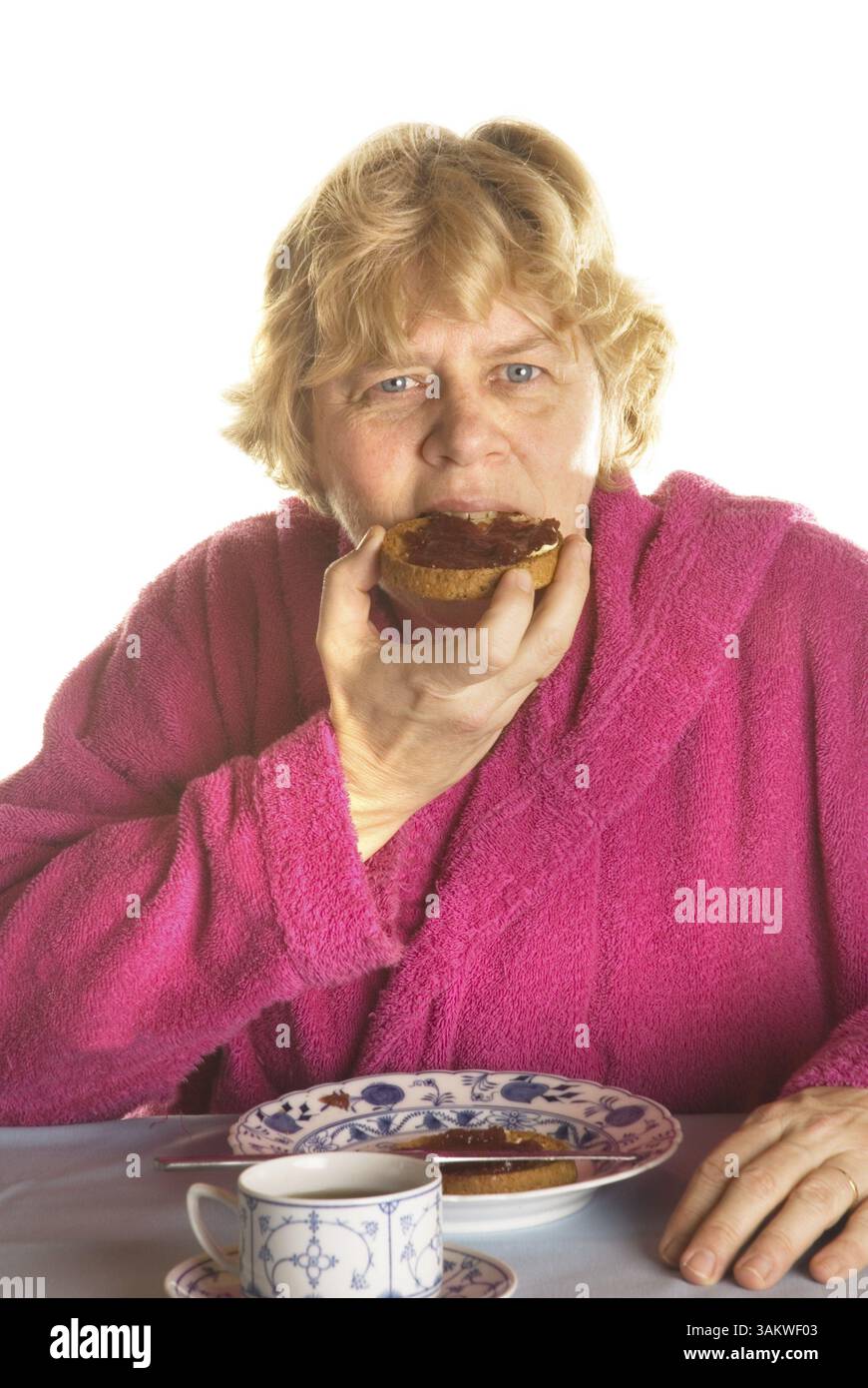 Senior woman is eating biscuits while having breakfast Stock Photo - Alamy