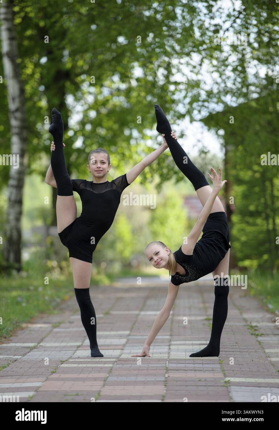 Two teen rhythmic gymnasts are showing their stretching and flexibility ...
