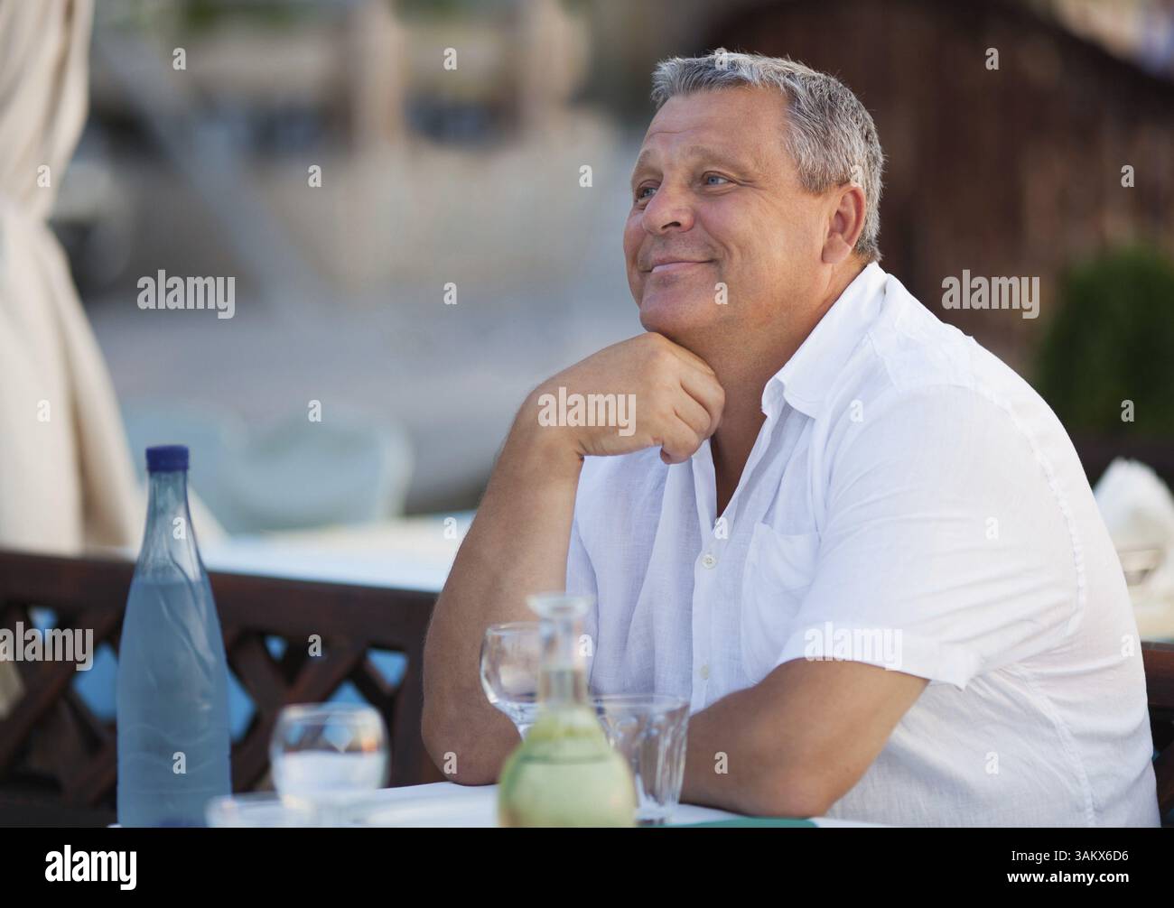 Smiling pensive middle-aged man at a restaurant sitting at a terrace ...