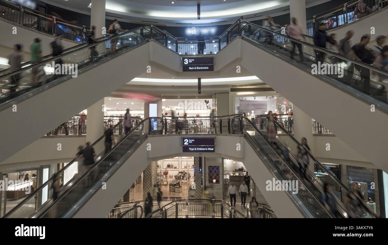 People riding up and down escalators in modern multistorey trade centre ...