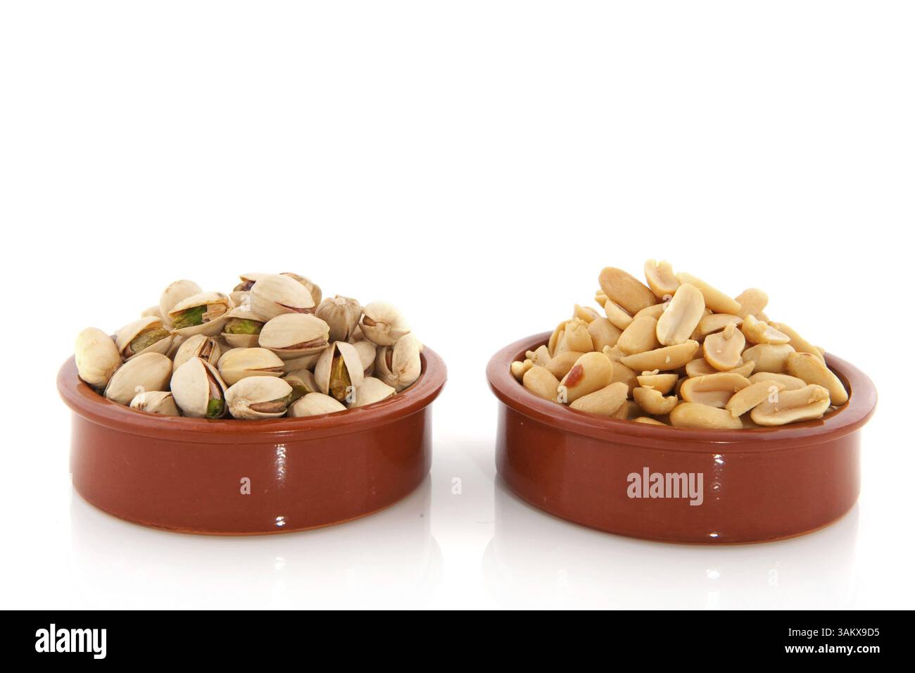 Pistachio nuts and peanuts in brown bowls Stock Photo - Alamy