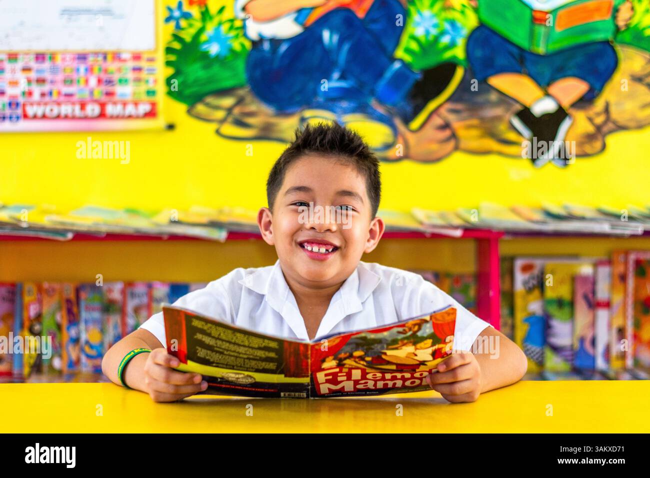 A young Filipino student reading a children's book inside a public ...