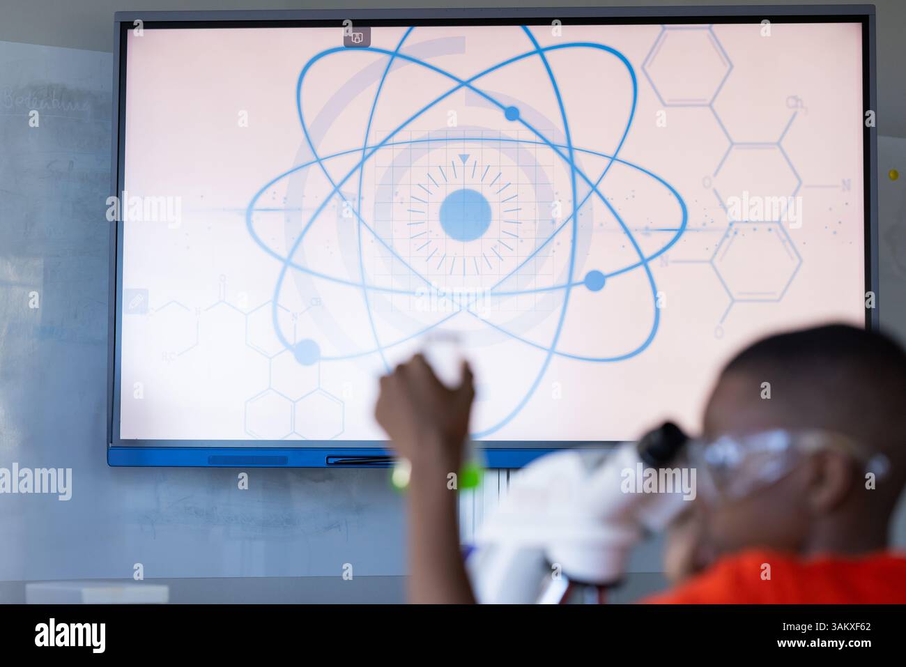 In school, student using microscope in science classroom, focusing on ...