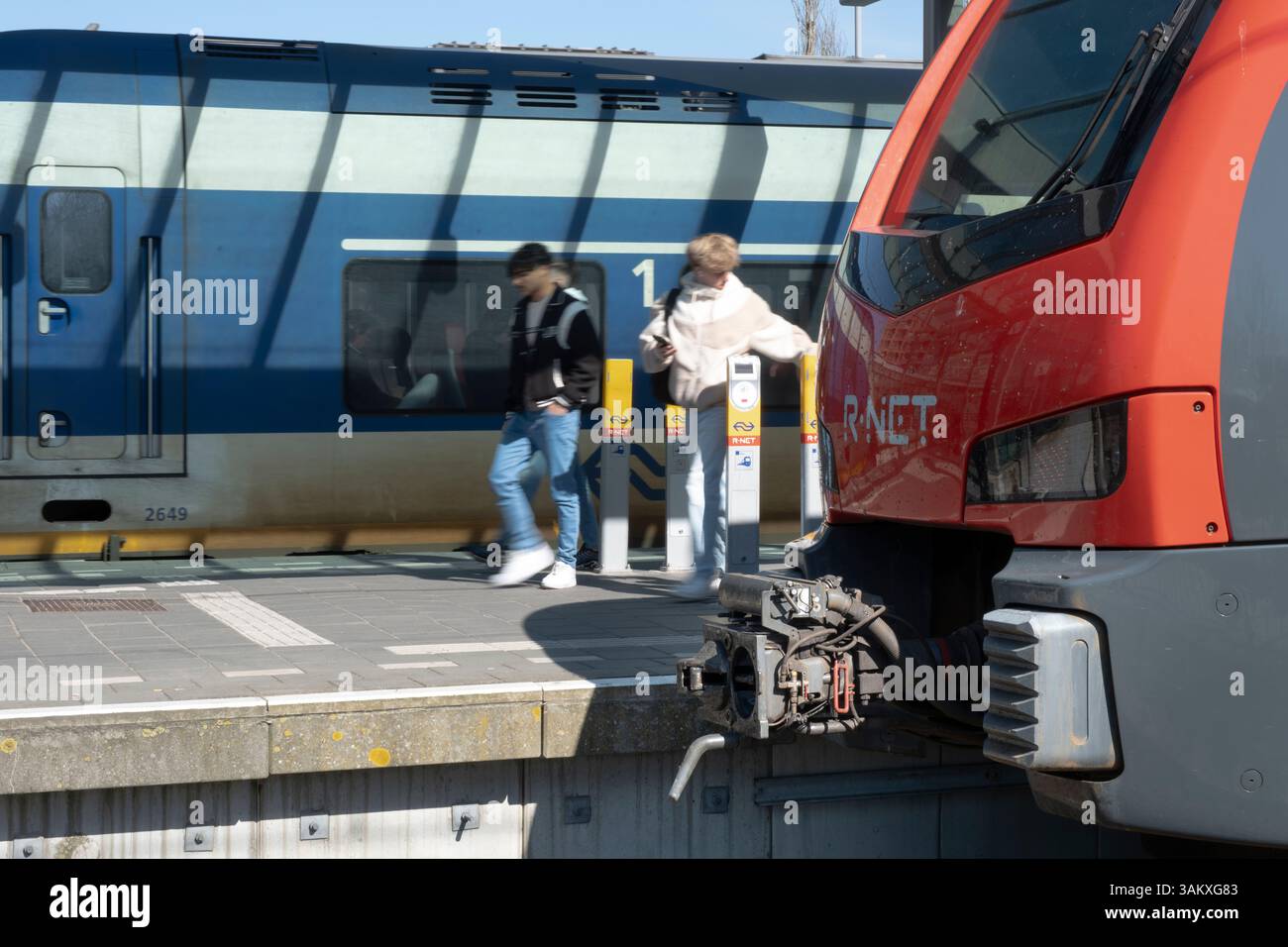 Young people leave a red train of R-net, the public transport network ...