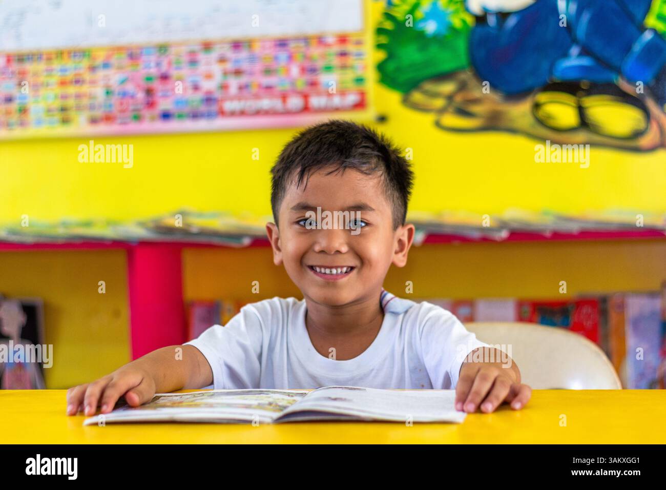 A young Filipino student reading a children's book inside a public ...