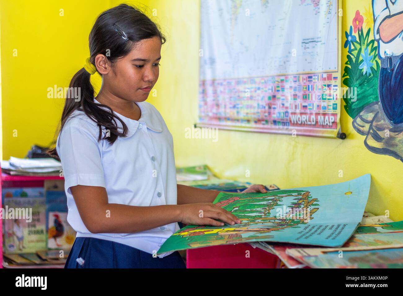 A young Filipino student reading a children's book inside a public ...