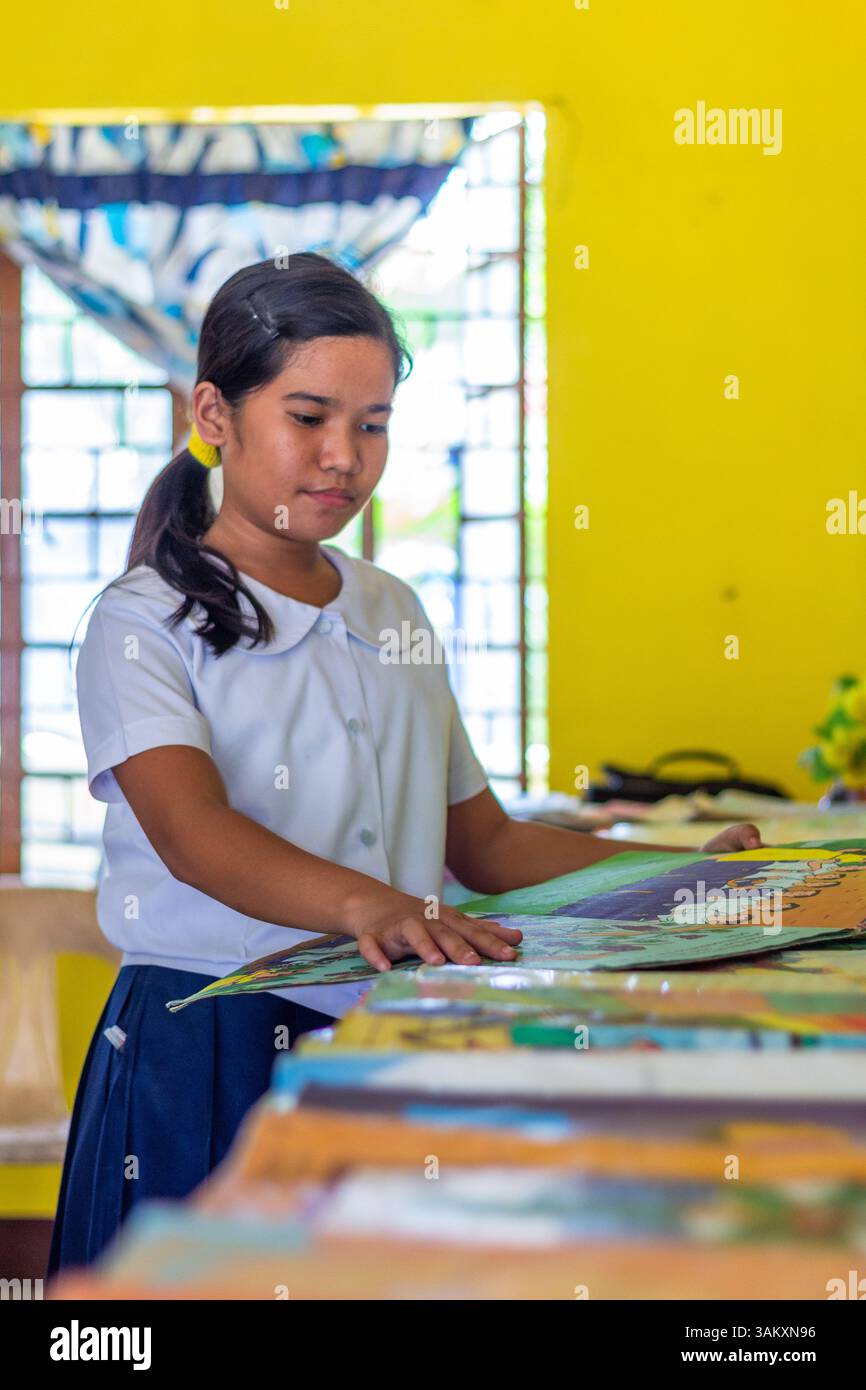 A young Filipino student reading a children's book inside a public ...