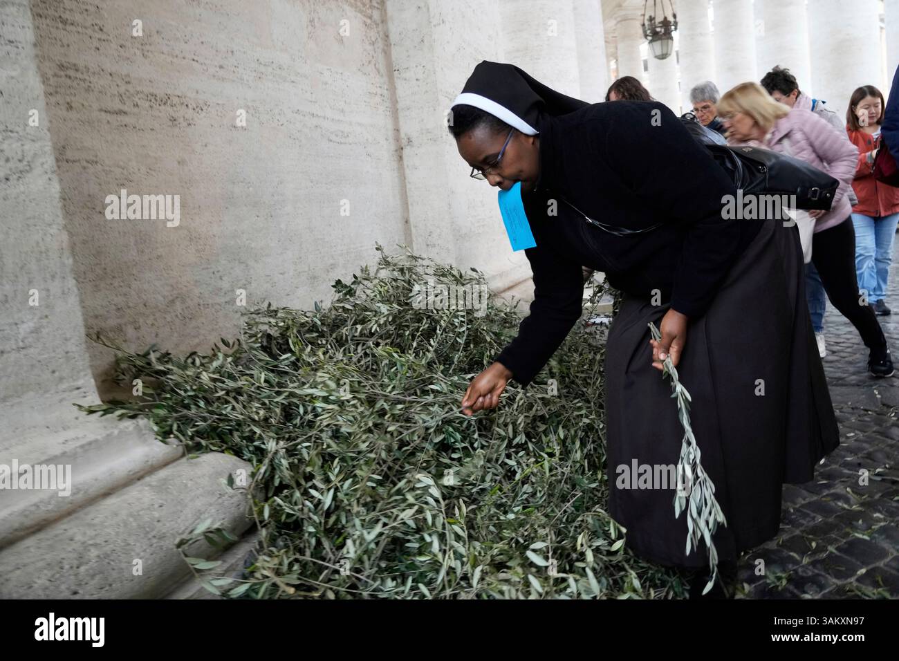 A nun collects olive tree twigs prior to the start of the Palm Sunday ...