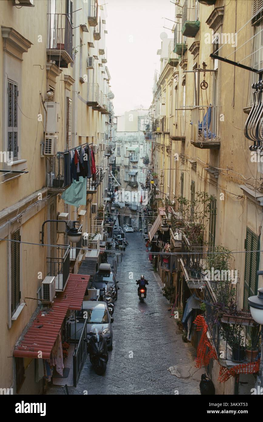 Narrow street in Naples with old houses, Italy. Motorbike driving along ...