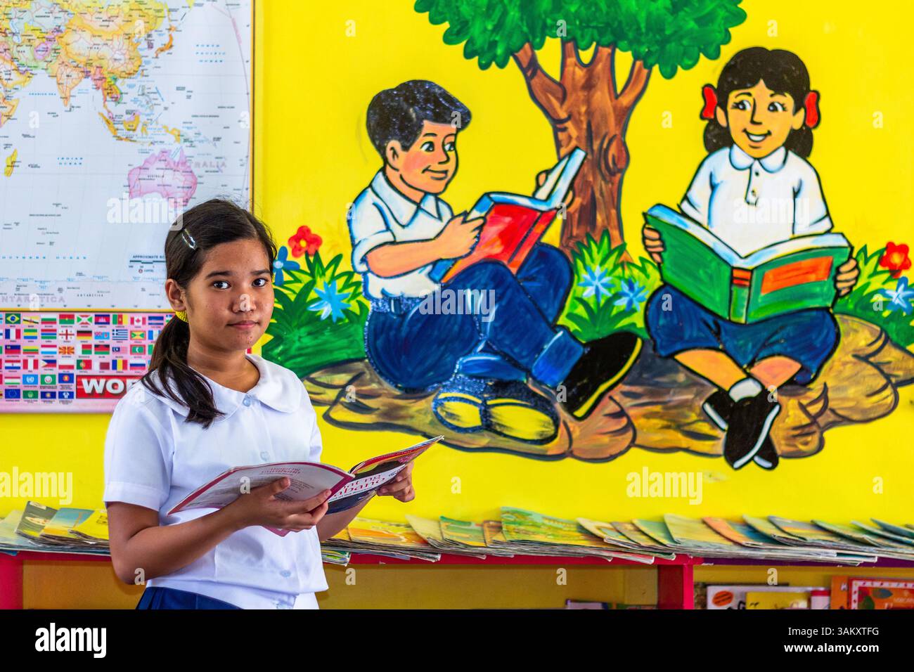 A young Filipino student reading a children's book inside a public ...