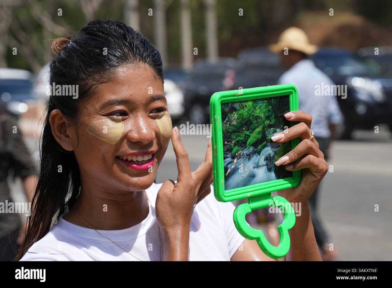 A girl applies Thanakha, traditional make-up, on her face as she takes ...