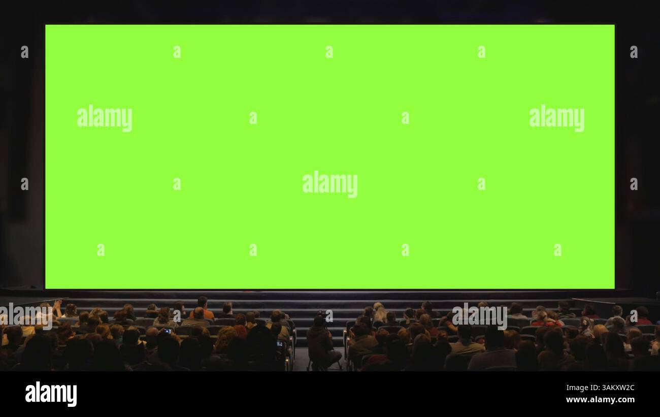 Viewers sitting in front of a big chroma key screen in the auditorium ...