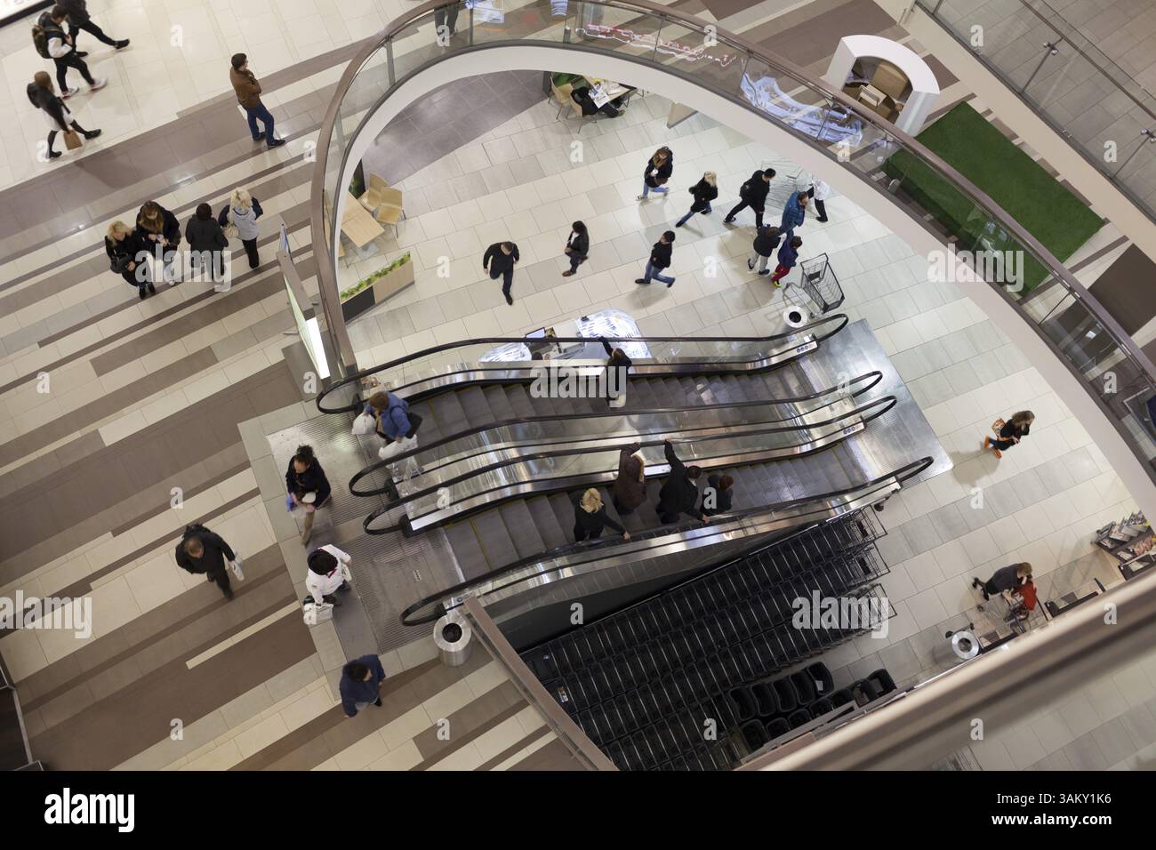 High angle shot of people walking around and riding escalator in modern ...