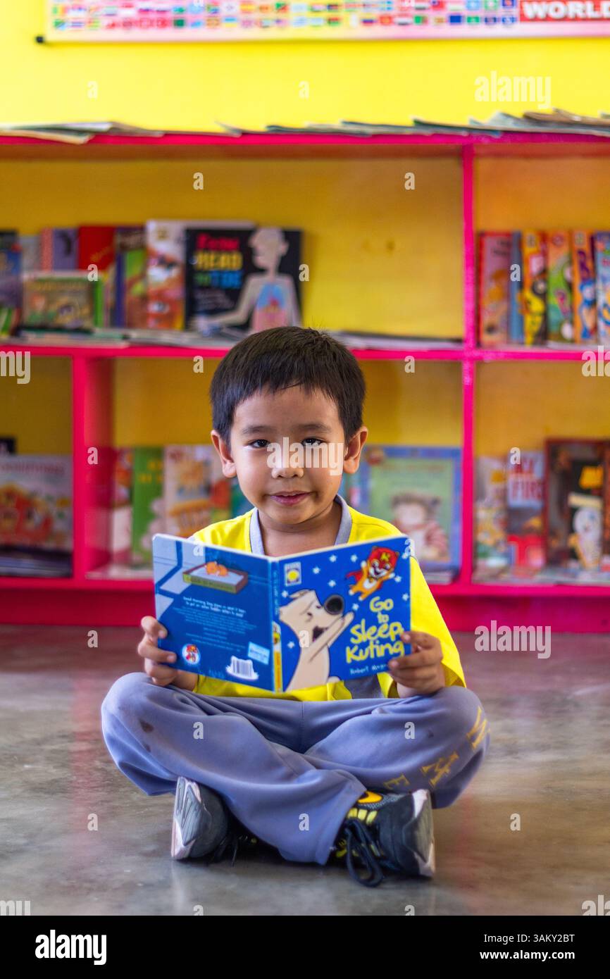 A young Filipino student reading a children's book inside a public ...