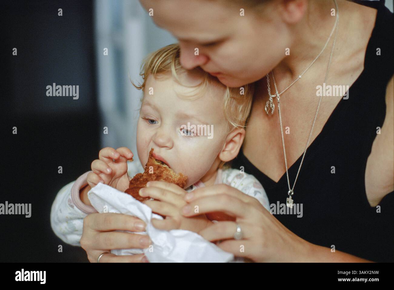 A mother feeds her baby with a croissant Stock Photo - Alamy