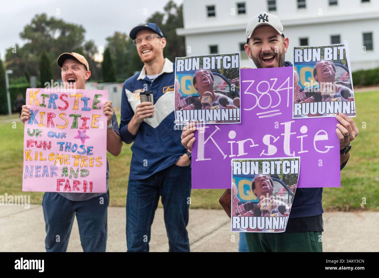 Supportive spectators line up at the race route, holding placards and ...
