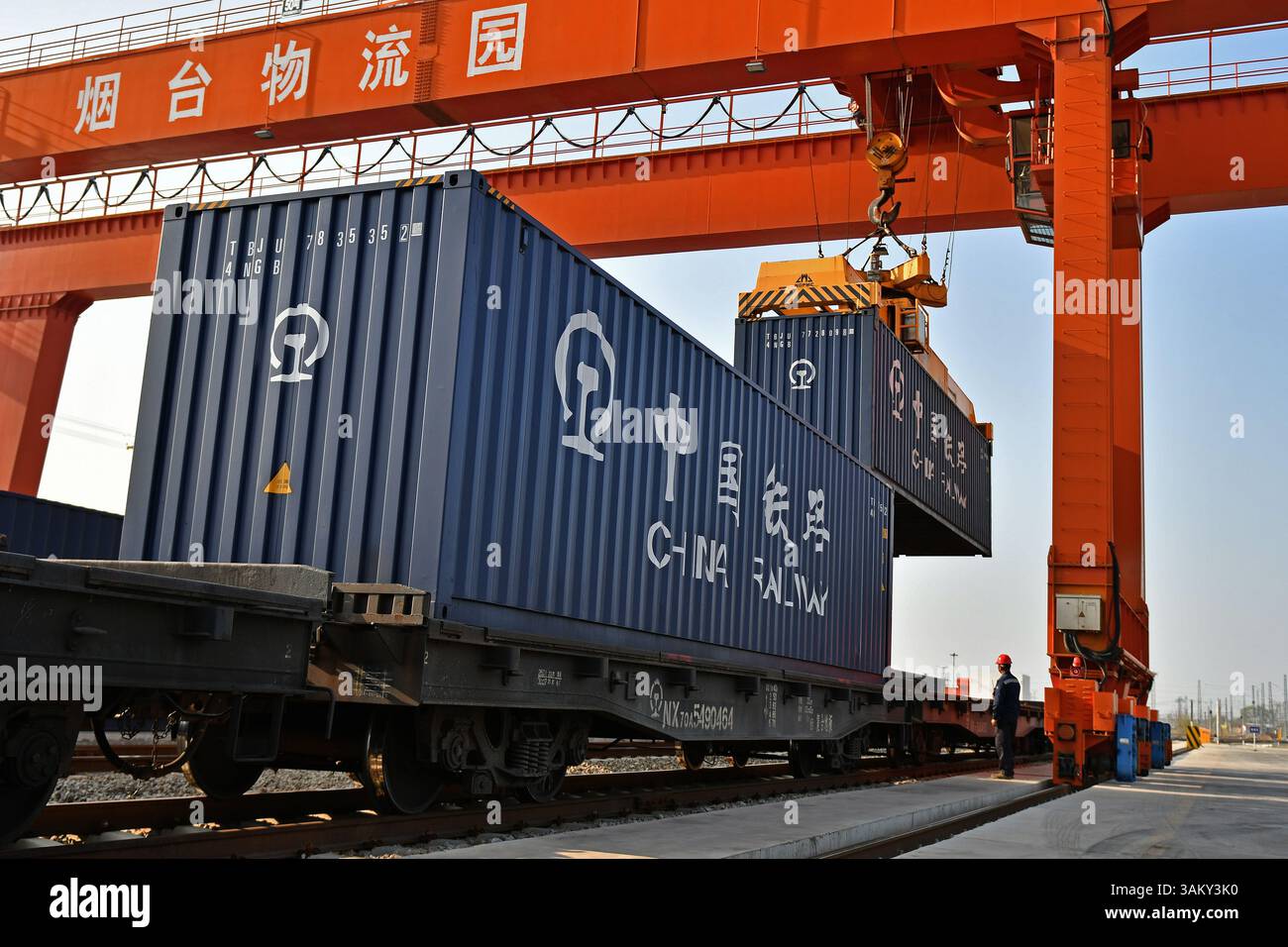 A railway container train is loaded into containers at a logistics park ...