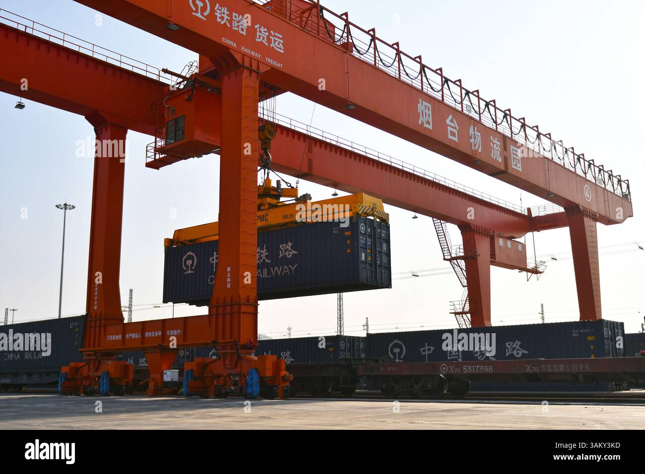 A railway container train is loaded into containers at a logistics park ...