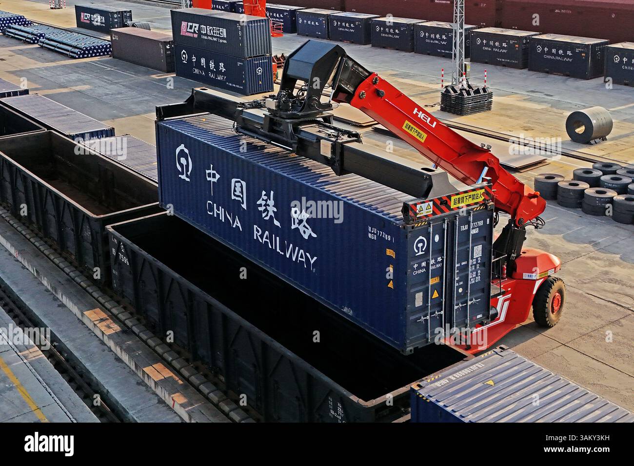 A railway container train is loaded into containers at a logistics park ...